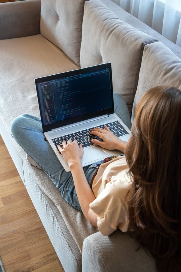Woman Working on a Laptop while Sitting on the Sofa. a Girl Programmer ...