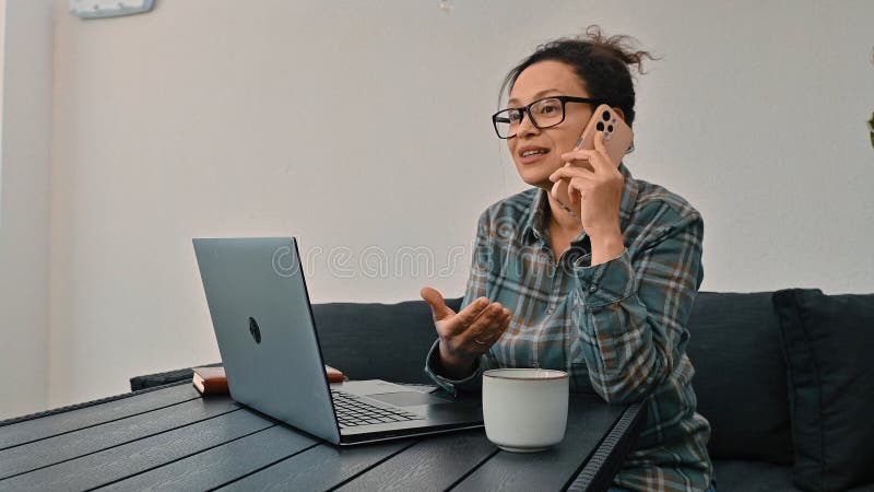 Woman Working Remotely Using Laptop and Phone in a Modern Setup Stock ...