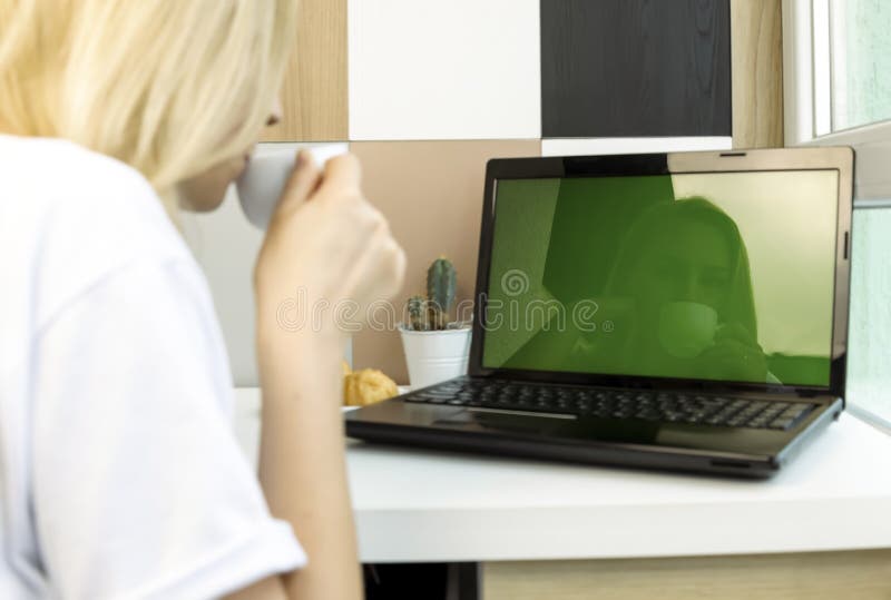 A Woman Works at a Computer and Drinks Coffee. Work at Home. Stock ...