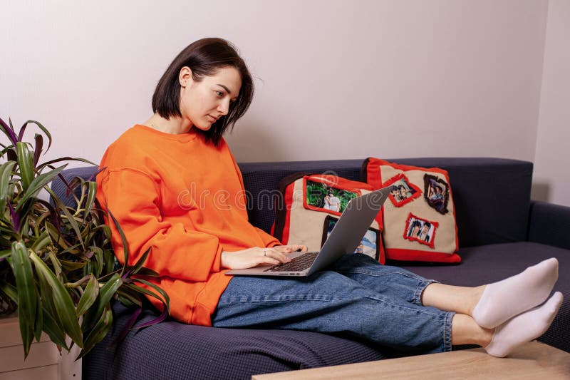 A Woman Works at the Computer at Home. a Woman Sits on a Couch with a ...