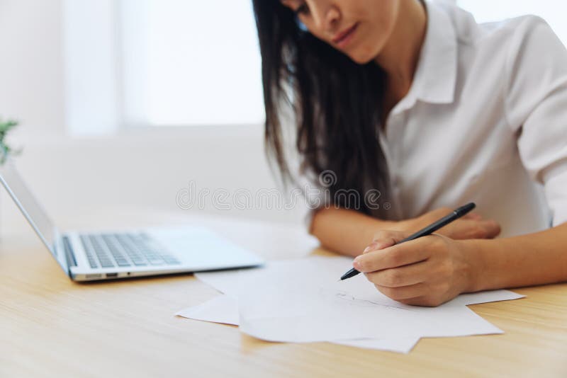 A Woman Works and Learns by Writing Down Text on Paper with a Pen and ...