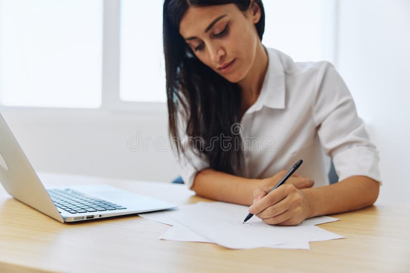 A Woman Works and Learns by Writing Down Text on Paper with a Pen and ...