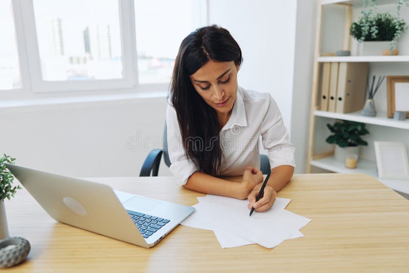 A Woman Works and Learns by Writing Down Text on Paper with a Pen and ...