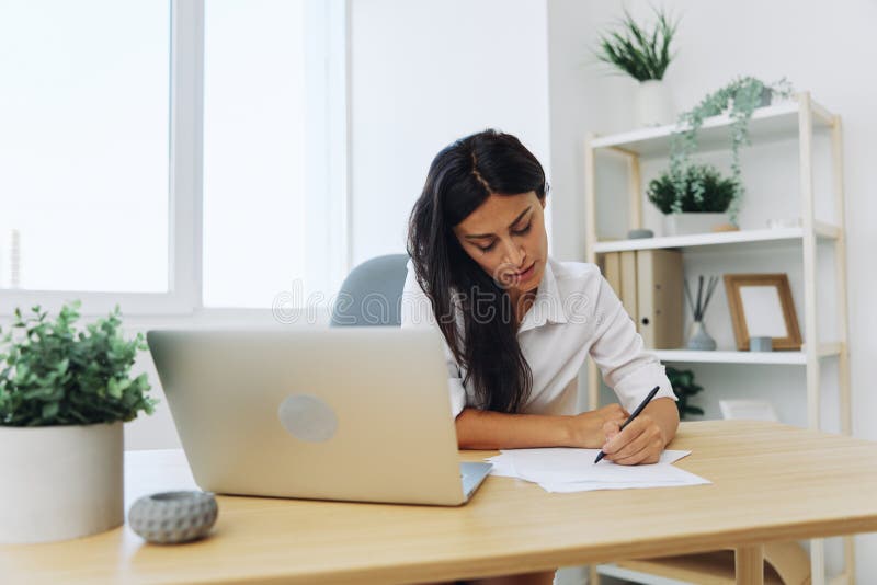 A Woman Works and Learns by Writing Down Text on Paper with a Pen and ...