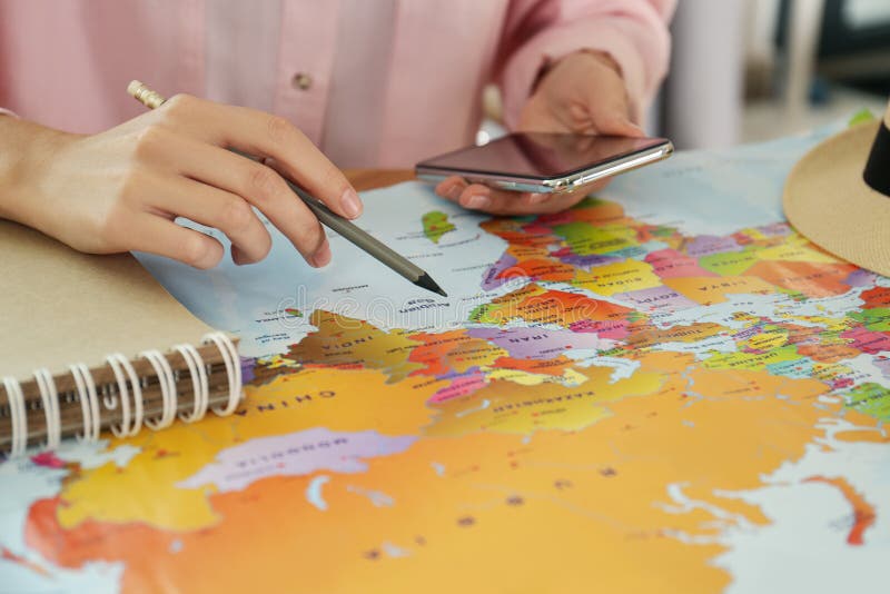 Woman with World Map and Smartphone Planning Trip at Table Stock Photo ...