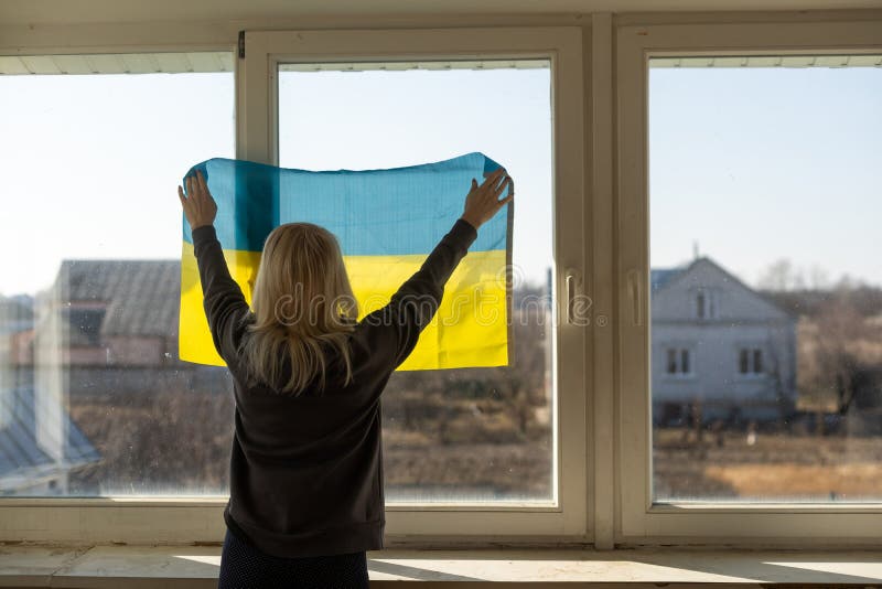 Woman Wrapped in Ukraine Flag Looking Out of the Window. Copy Space ...