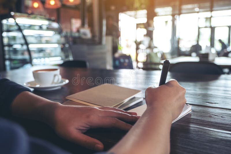 A Woman Writing on Blank Notebook with Coffee Cup on Table in Cafe ...