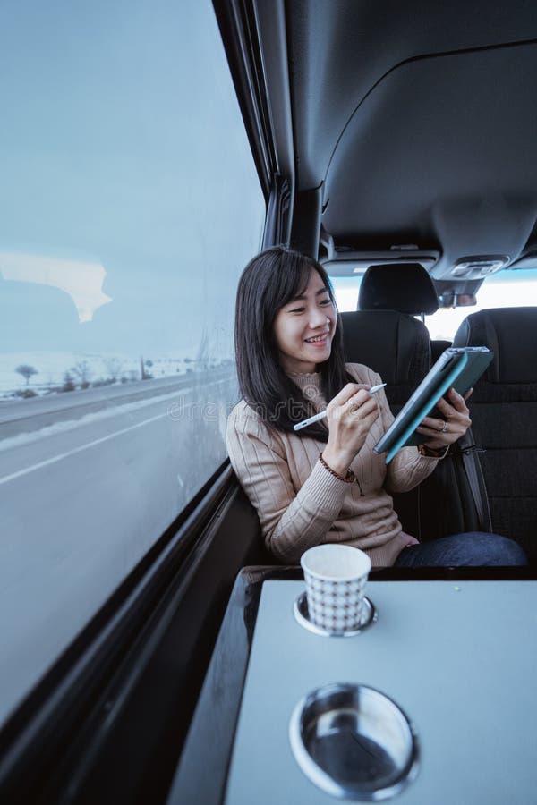Woman Writing a Note on Her Tablet while Sitting Inside a Car Stock ...
