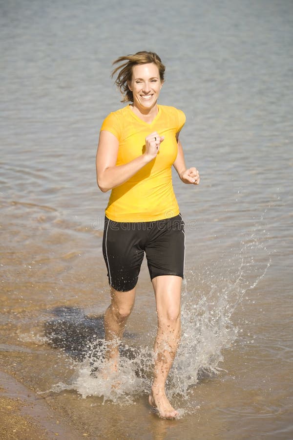 Woman in Yellow Running in Water Stock Photo - Image of woman, female ...