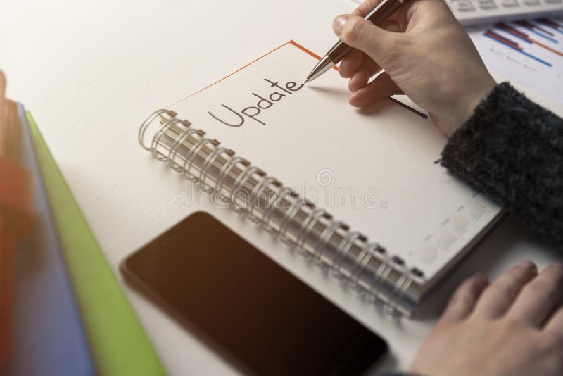 Womans Hand Writing Word Update in a Notebook on a Desk. Project Stock ...