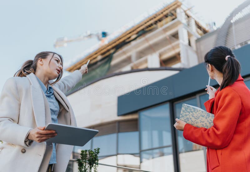 Two Female Entrepreneurs Discussing a Construction Project Outside a ...