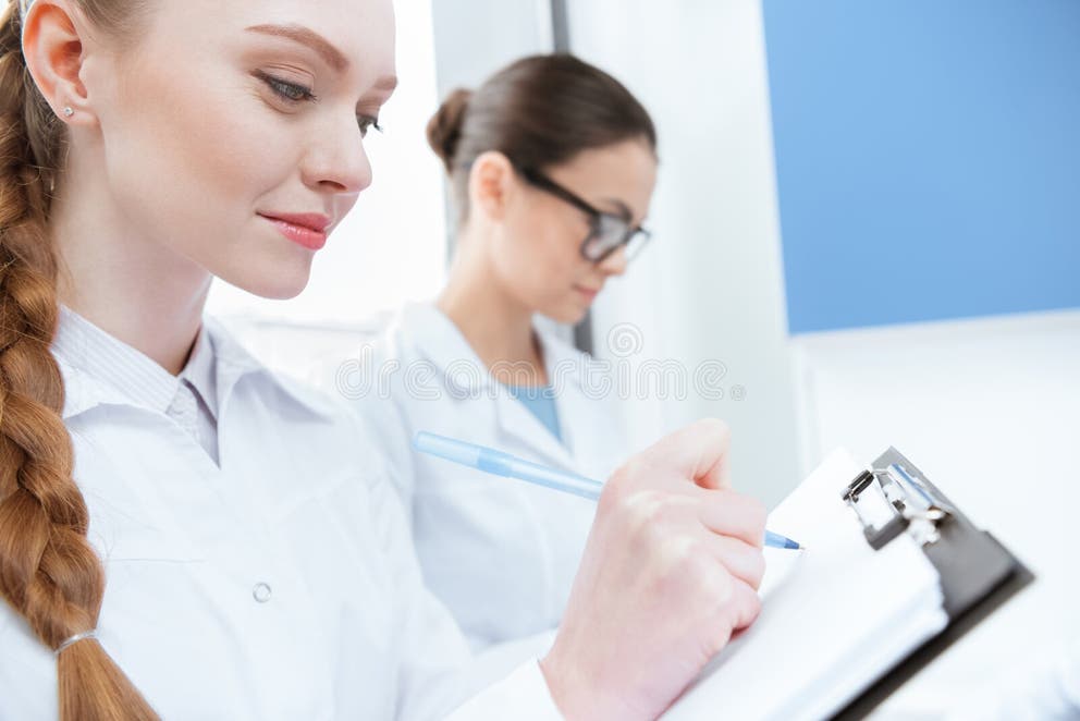 Women Scientists in White Coats Taking Notes in Laboratory Stock Photo ...