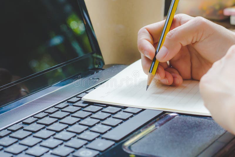 Women are Using Pencil To Write Books. Placed on a Notebook Computer on ...