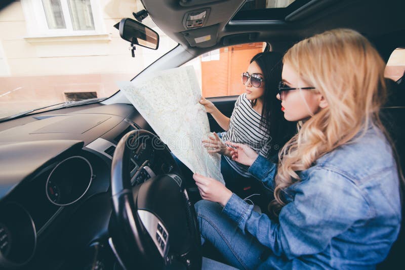 Women on Vacation Looking at Map for Directions while Driving in Car ...