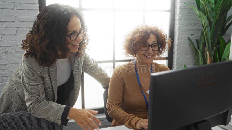 Women Working Together in an Office Setting with Computers, Displaying ...