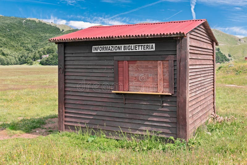 Rustic Ticket Booth Windows with Open Turquoise Shutters in Stucco Wall ...