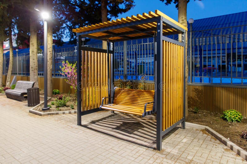 A Wooden Bench with a Metal Frame is Sitting in Front of a Fence Stock ...