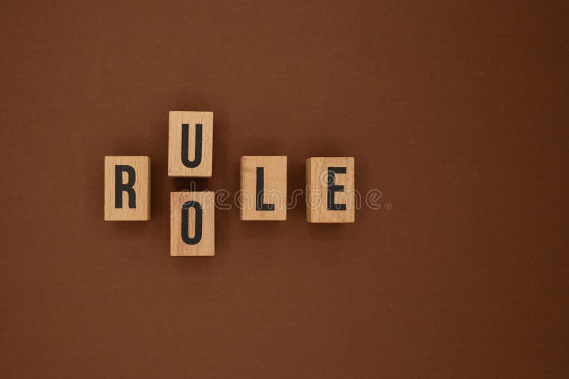 Wooden Blocks Forming the Words RULE and ROLE on Brown Background ...