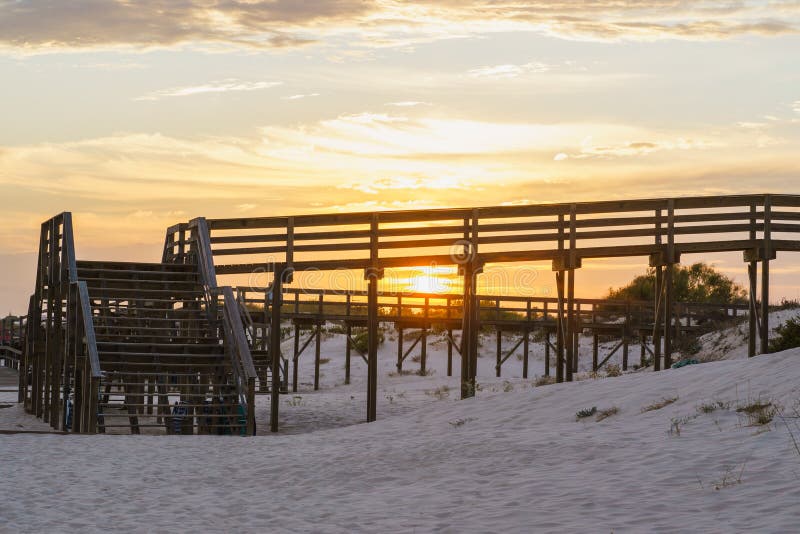 Wooden Boardwalk Over Sandy Dunes with the Sun Setting in the ...