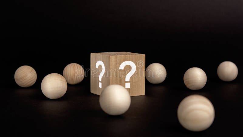 Wooden Cube with a Question Mark Surrounded by Wooden Balls on a Black ...