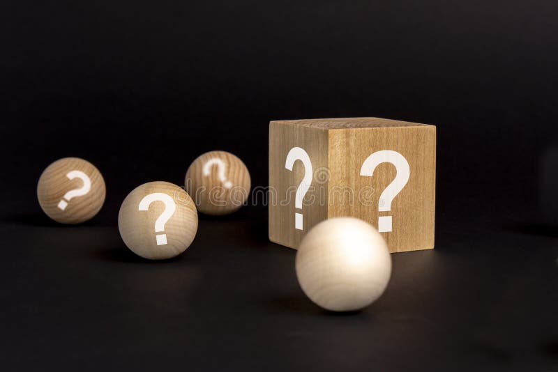 Wooden Cube with a Question Mark Surrounded by Wooden Balls on a Black ...