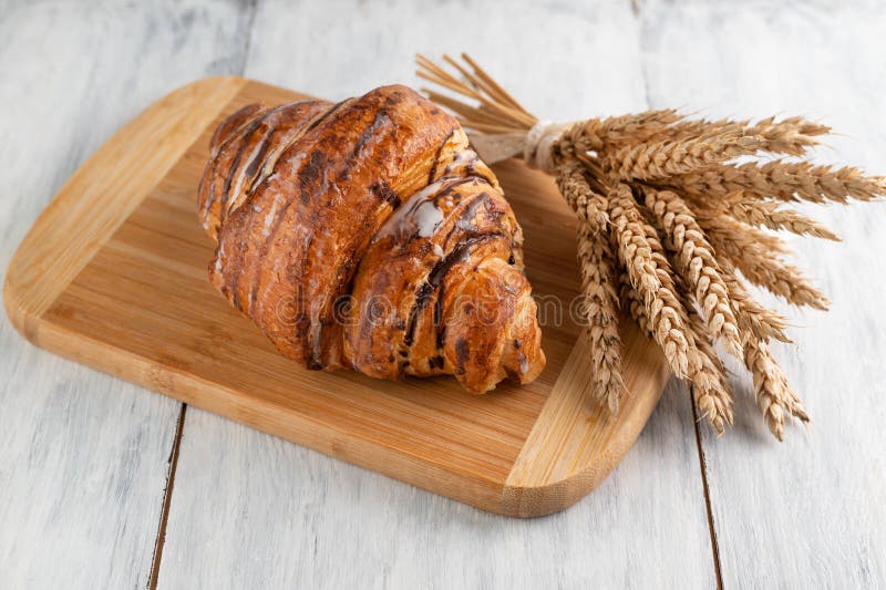 On a Wooden Cutting Board, a Croissant and Wheat Ears on a Light Table ...