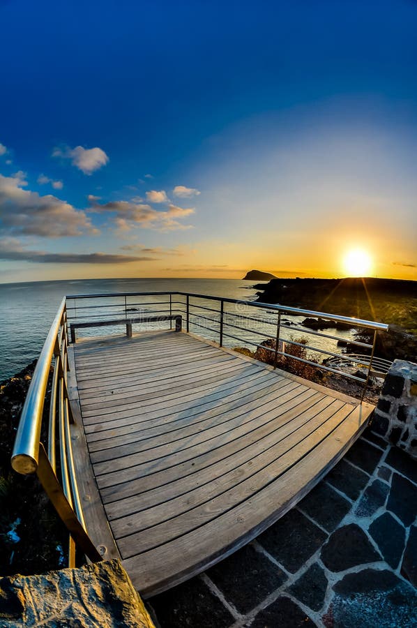 A Wooden Deck Overlooking the Ocean with a Beautiful Sunset in the ...