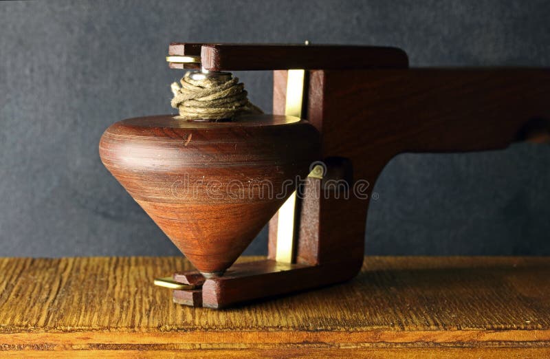 WOODEN HANDCRAFTED SPINNING TOP POSED in a LAUNCHER Stock Image - Image ...