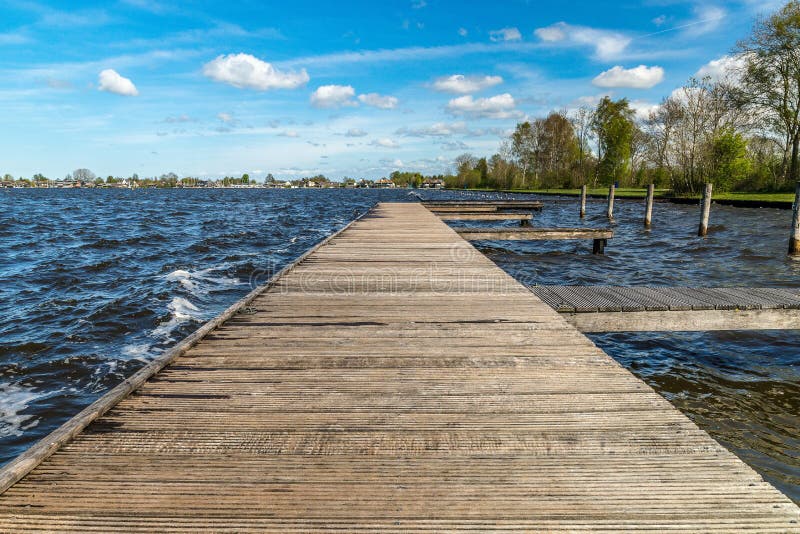 Wooden Pathway Over the Water with Green Trees on the Side Under a Blue ...