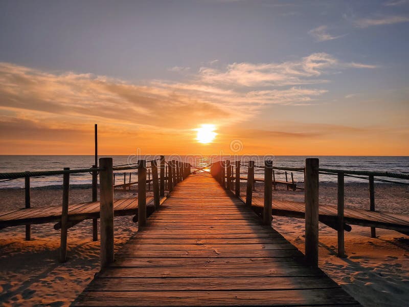 Wooden Pier on a Beach during a Beautiful Orange Sunset Stock Image ...