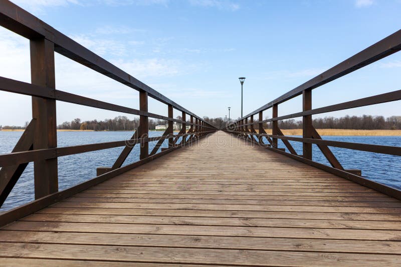 A Wooden Plank Bridge Over a River Faces a Perspective with a Blue Sky ...