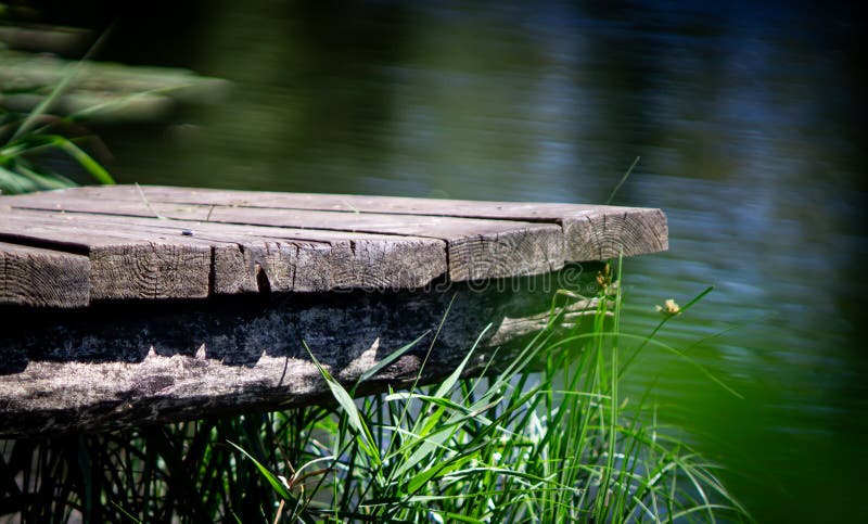 Wooden Platform Extends Over a Calm River, Partially Concealed by Lush ...