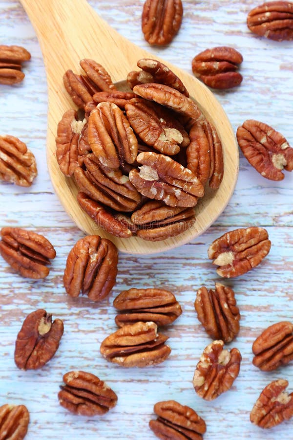 Wooden Spoon Full of Pecan Nuts with Many Kernels Scattered on Blue ...
