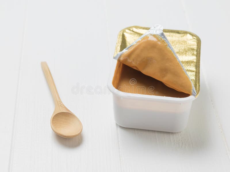 A Wooden Spoon and an Open Container of Peanut Paste on a White Table ...