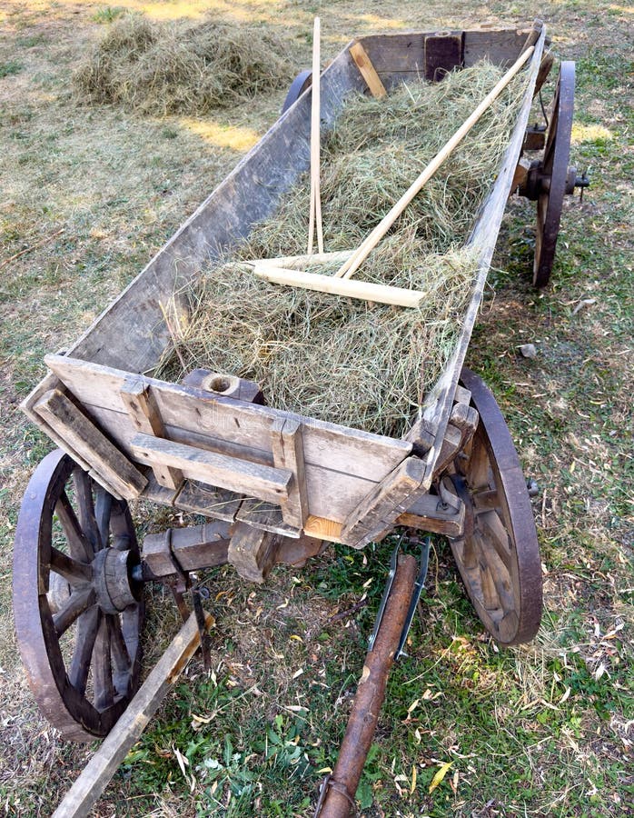 A Wooden Wagon with Hay in it and a Rake Leaning on it Stock Photo ...