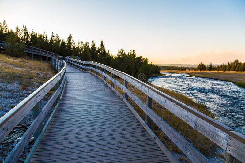 A Wooden Walkway Over a River Next To Trees and Hills Stock Image ...