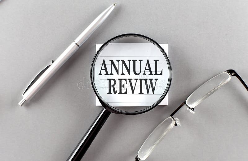 Word ANNUAL REVIEW on Sticky through Magnifier on Grey Background Stock ...