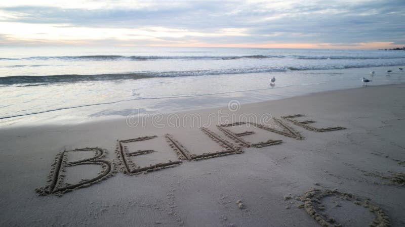 The Word "Believe" Written in the Sand on a Beach, with Gentle Waves in ...