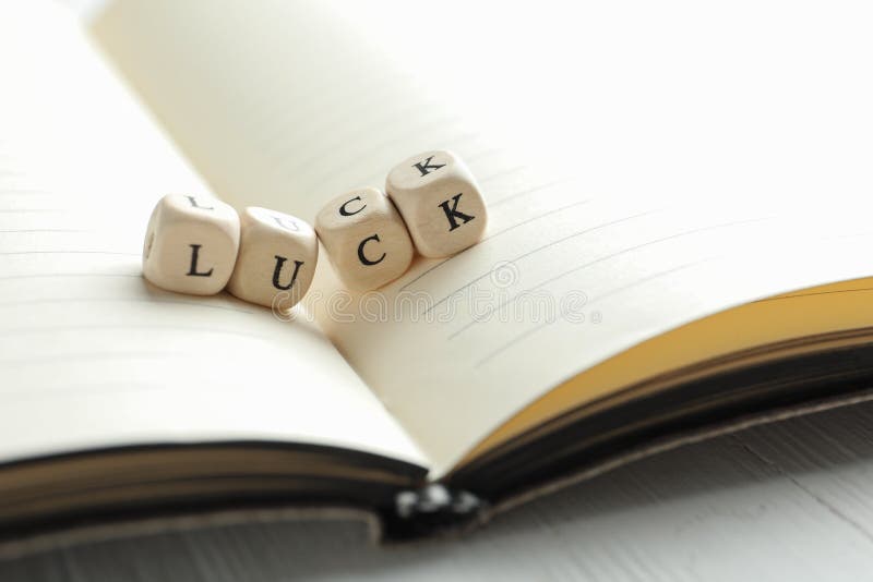 Word LUCK Made with Wooden Cubes and Open Notebook on Table, Closeup ...