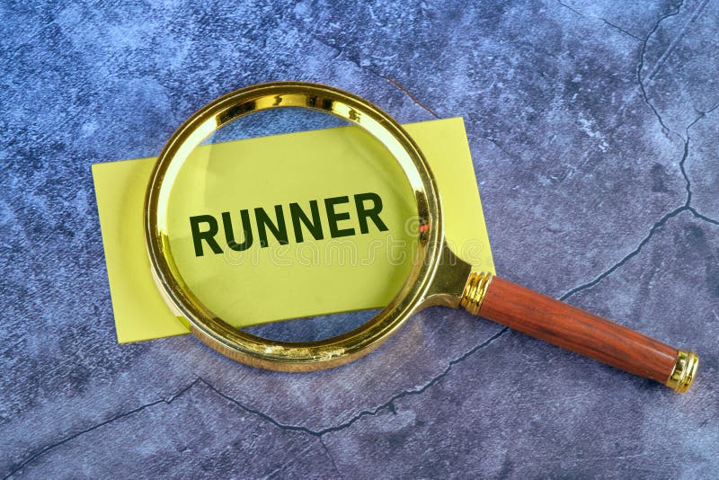 The Word RUNNER through a Magnifying Glass on Yellow Paper on an ...