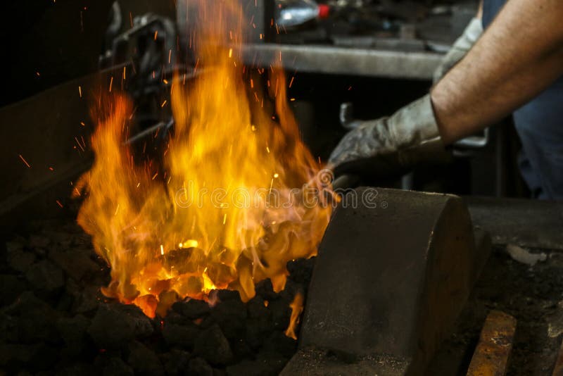 A Blacksmith at Work with Glowing Irons. Hot Iron Forge, a Black Stock ...