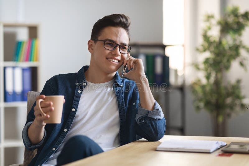 Work Break. Millennial Guy Relaxing in Office with Cellphone and Coffee ...