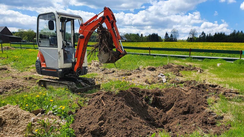 Work on the Construction Site of a House. the Excavator Digs Out Roots ...