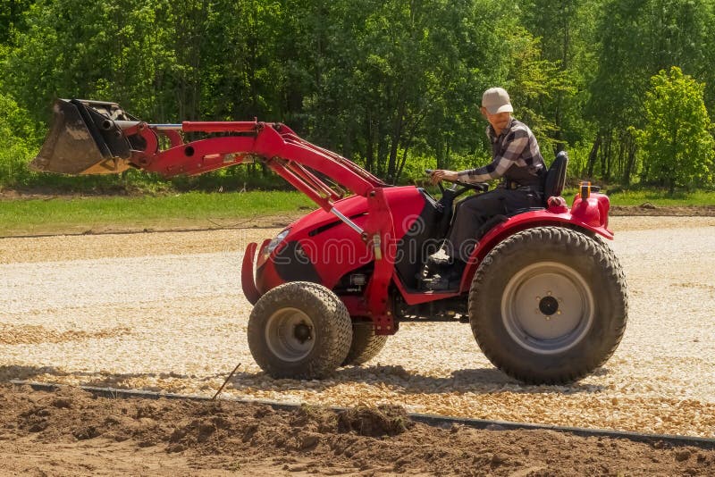 Work on a Construction Site. a Small Tractor Picks Up Crushed Stone ...