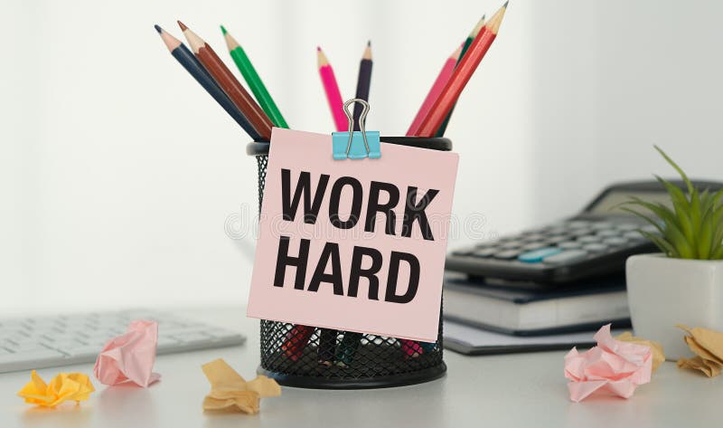 WORK HARD Text on Yellow Sticky Note and Desk with Notepad and ...