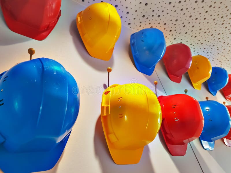 Work Helmets of Different Colors Hang on Hooks on the Wall. Stock Image ...