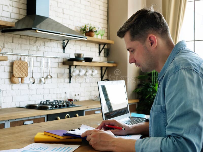 Work from Home Concept. a Young Man Works with Documents in the Kitchen ...