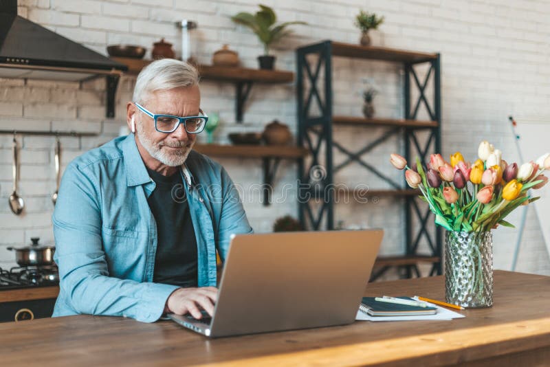 Work at Home. Mature Man with Laptop at the Table in the Kitchen Stock ...