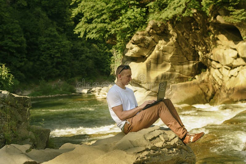 Work in Nature Concept. Man with Notebook Sitting at the Bank of River ...