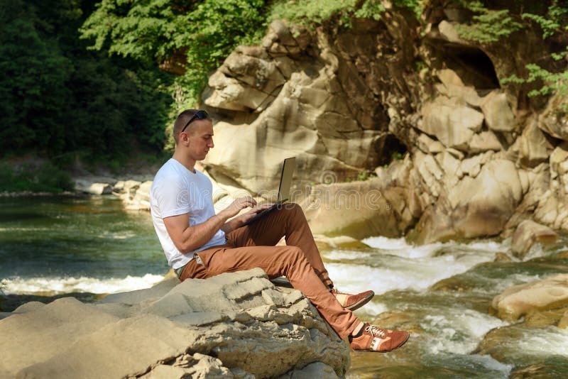 Work in Nature Concept. Man with Notebook Sitting at the Bank of River ...